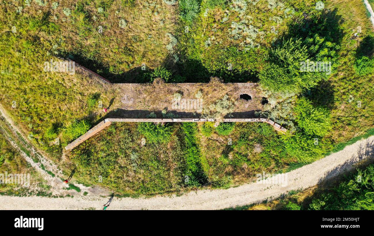 An aerial top view of an old stone bridge near a dry river surrounded ...