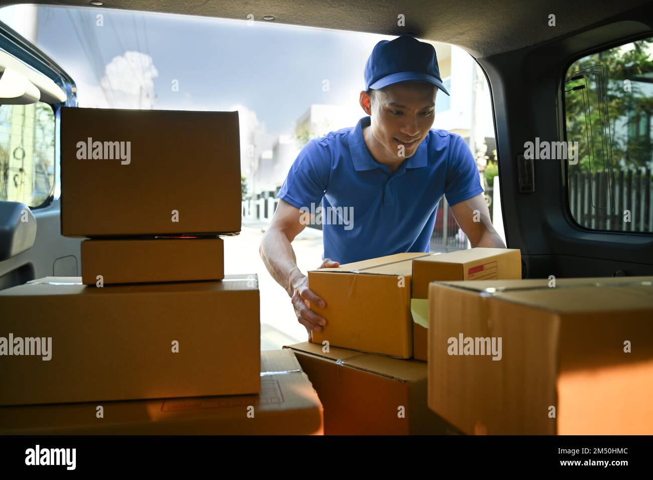 Asian delivery men unloading cardboard boxes from cargo van. Delivery ...