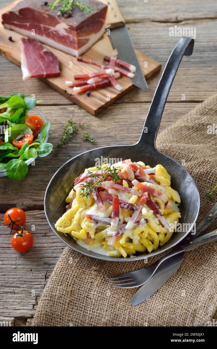 Hearty spaetzle with cheese sauce and South Tyrolean bacon served in an ...