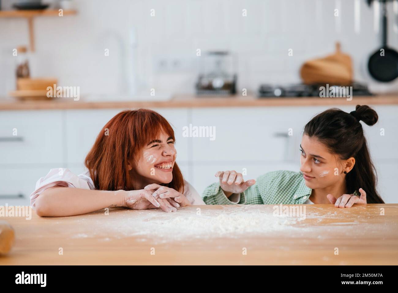Two beautiful women play with flour in the kitchen Stock Photo - Alamy