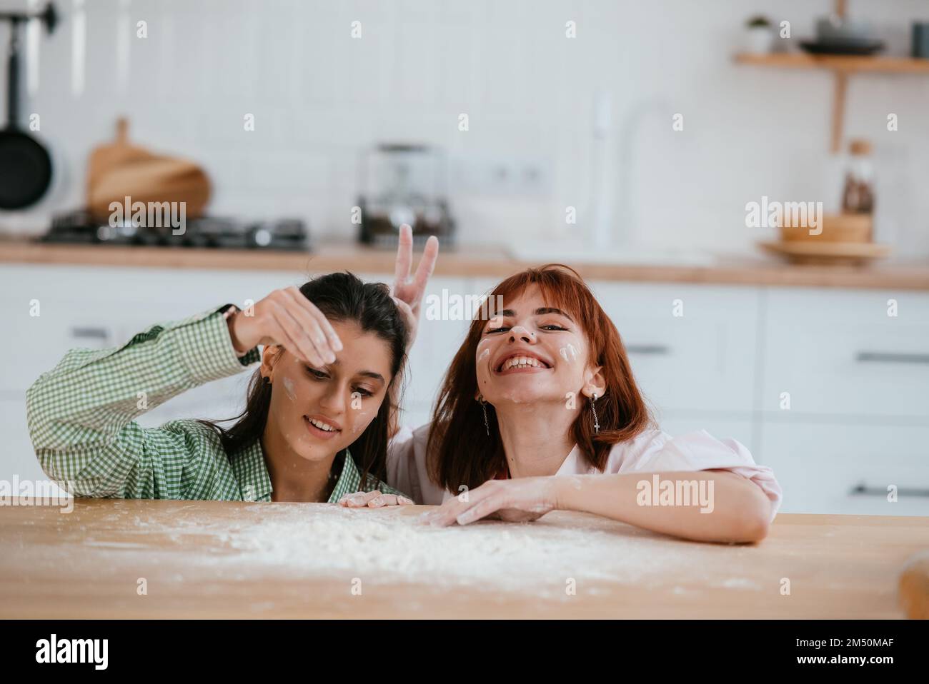 Two beautiful women play with flour in the kitchen Stock Photo - Alamy