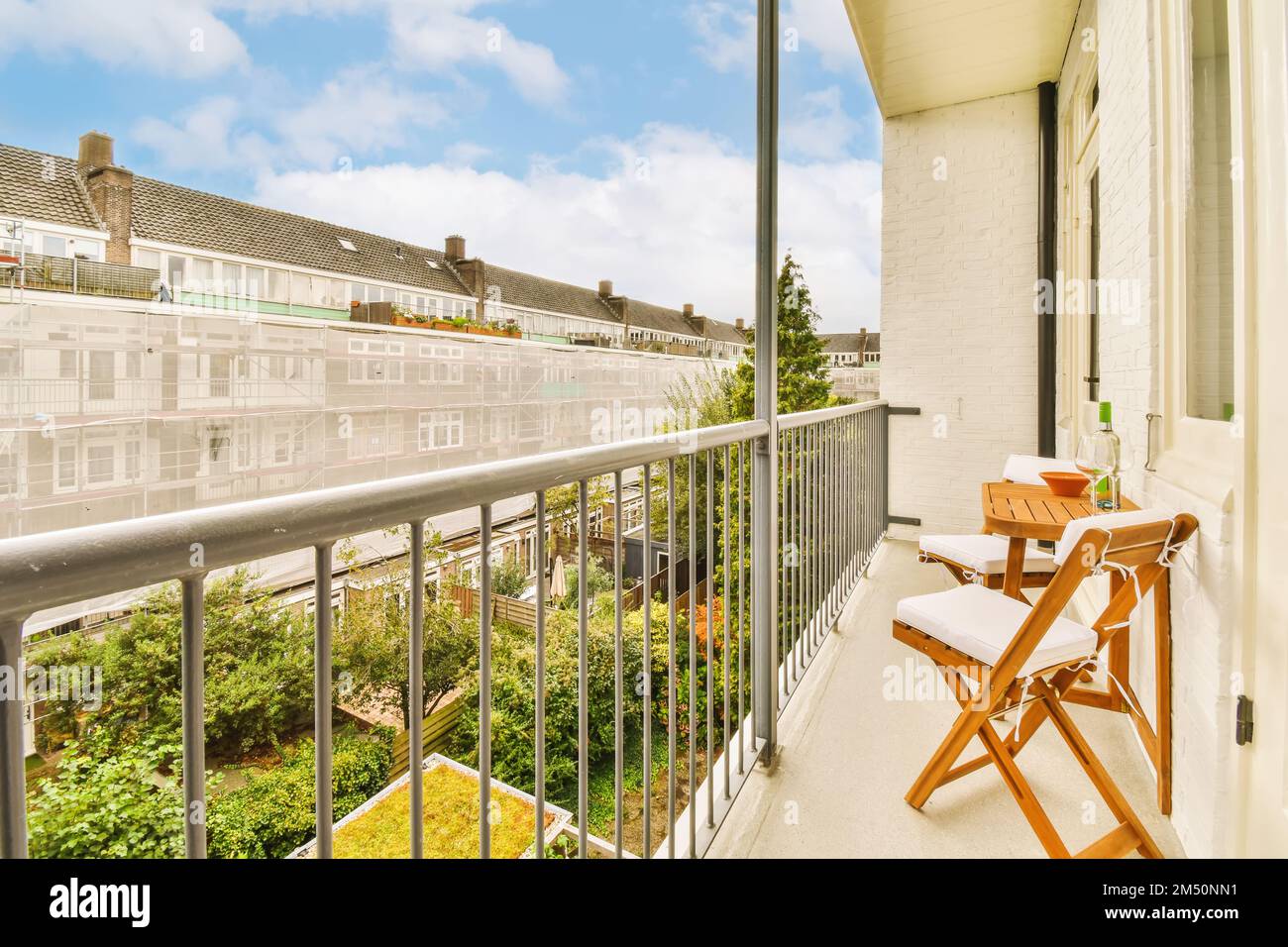 a balcony with a chair and table on the left hand side, looking out to ...