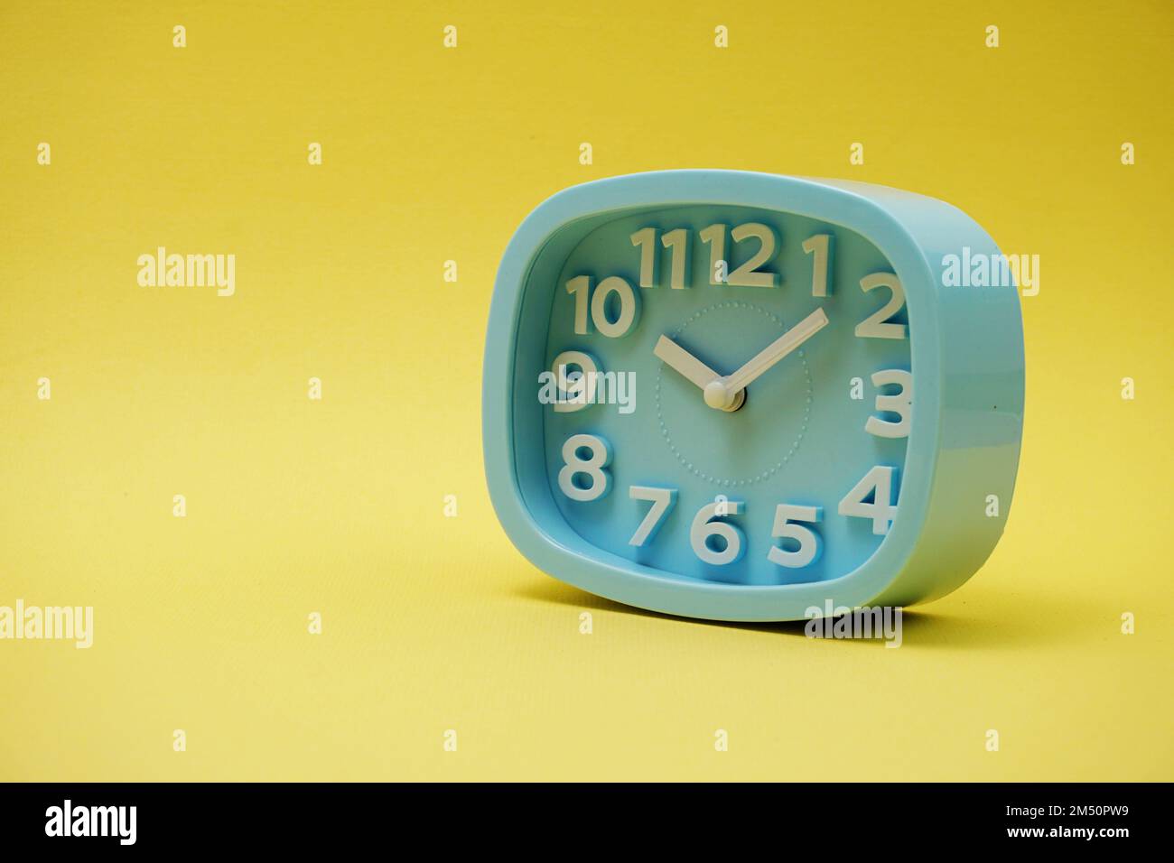 light blue alarm clock with space copy on yellow background Stock Photo ...