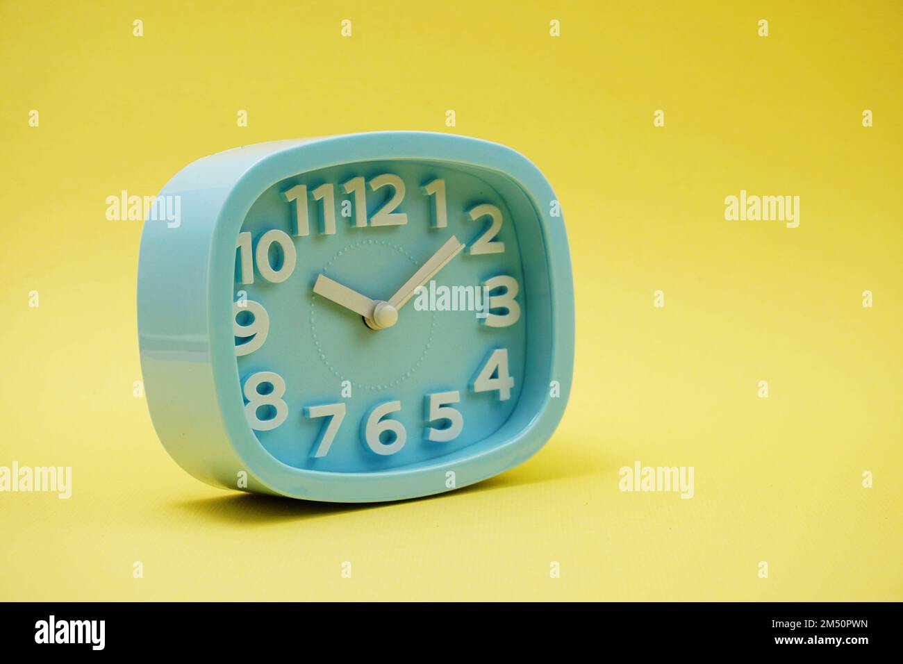 light blue alarm clock with space copy on yellow background Stock Photo ...