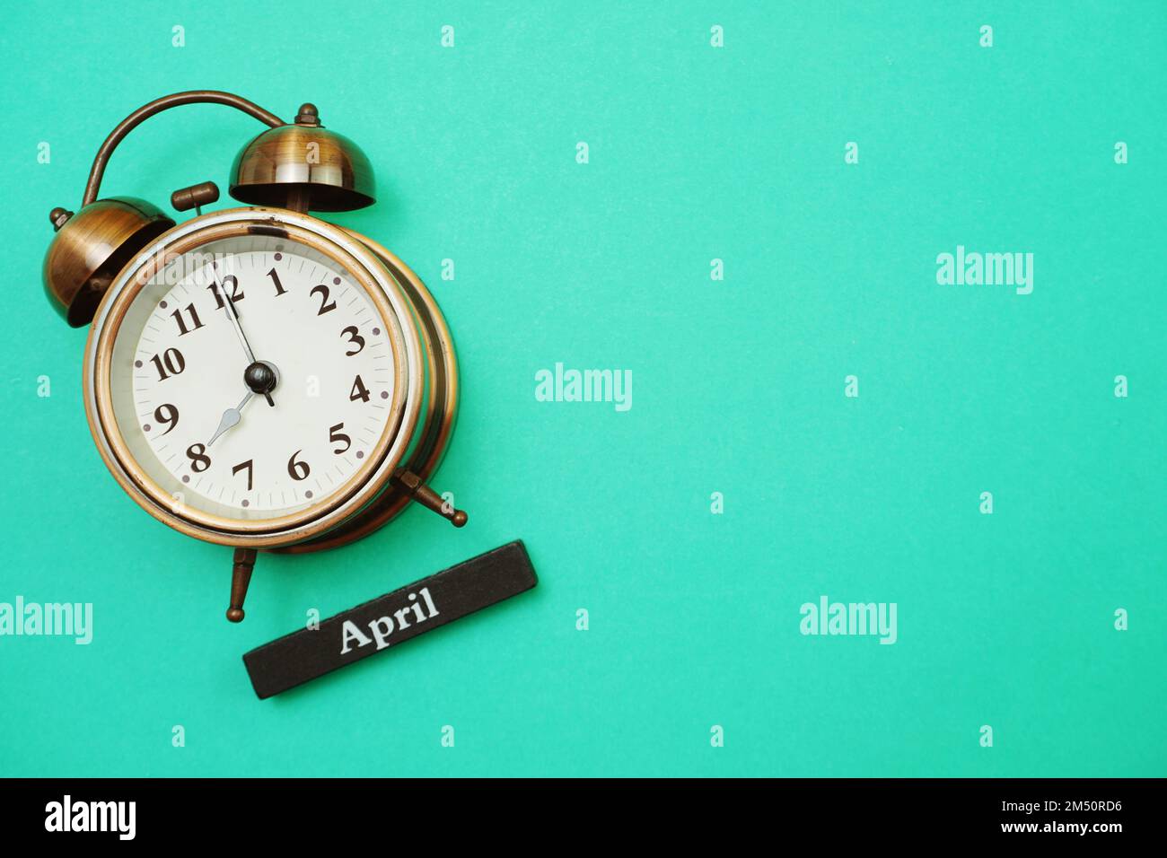 Alarm clock and April calendar with space copy on green mint background ...