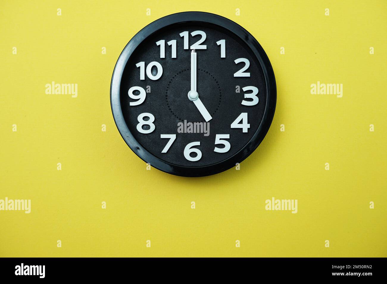 Black round clock showing five o'clock on yellow background Stock Photo ...