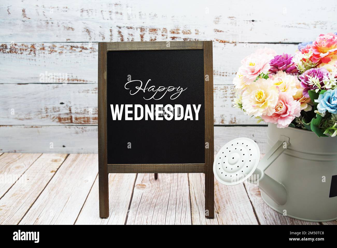 Happy Wednesday text on blackboard easel with flower bouquet on wooden ...