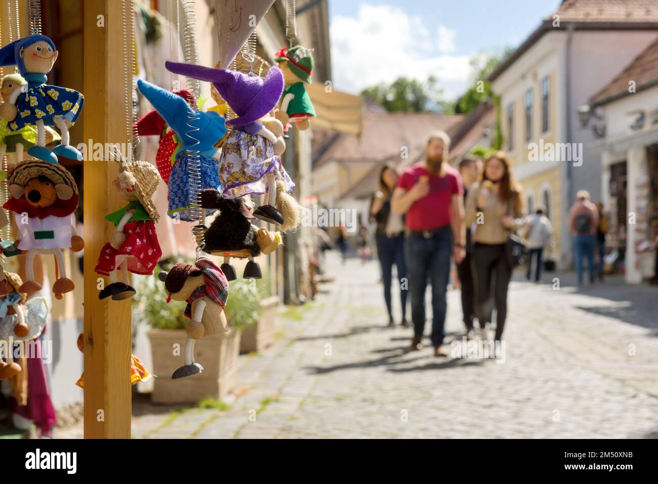 Defocused people walking along old european town street, dolls hanging ...
