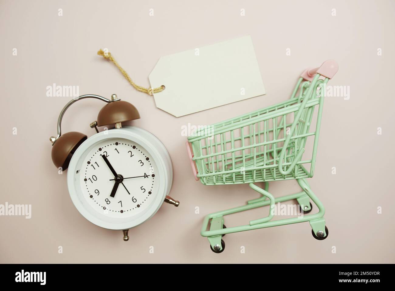 Empty Price tag with alarm clock and shopping trolley cart on pink ...