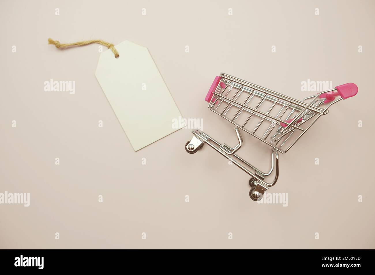 Price tag and shopping trolley cart on pink background Stock Photo - Alamy