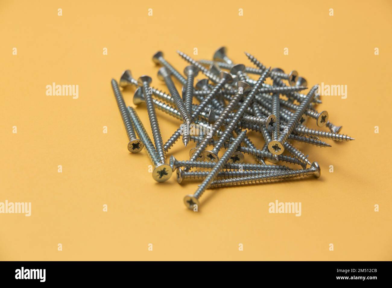 A Closeup of a bunch of screws and bolts on a yellow background Stock ...