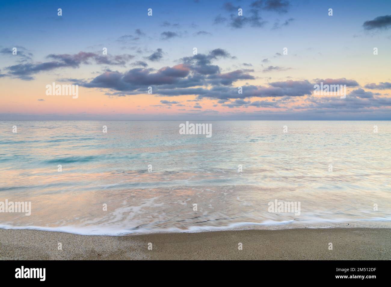View of calm turquoise ocean water under a olorful sunset sky with calm ...