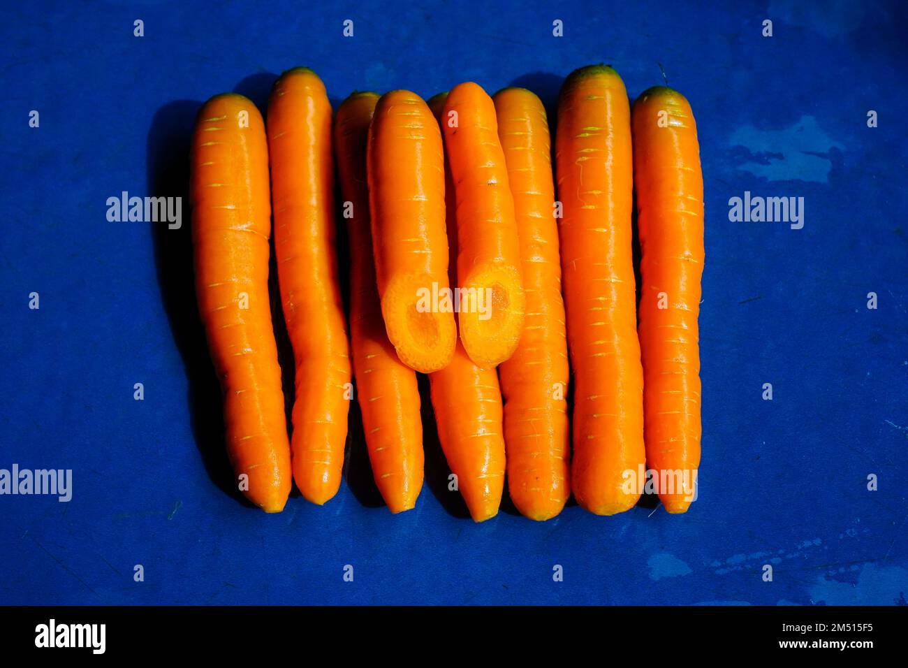 Bright orange carrots on a dark blue surface Stock Photo - Alamy