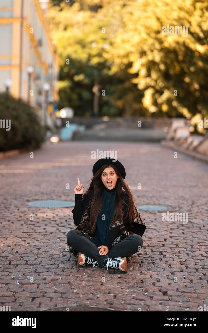 Young woman sitting at city show finger up, new idea Stock Photo - Alamy