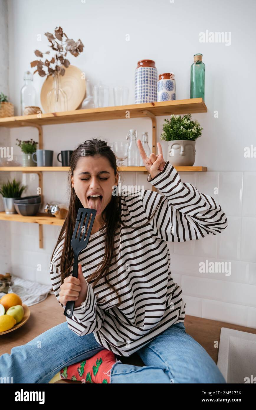 Funny woman singing into spatula, holding spatula as microphone Stock ...