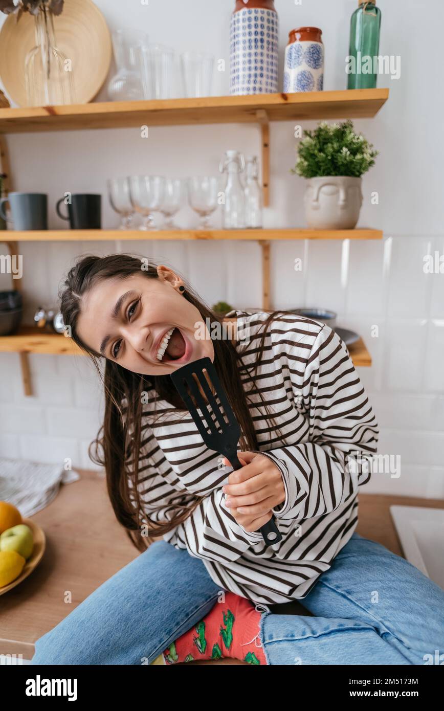 Funny woman singing into spatula, holding spatula as microphone Stock ...