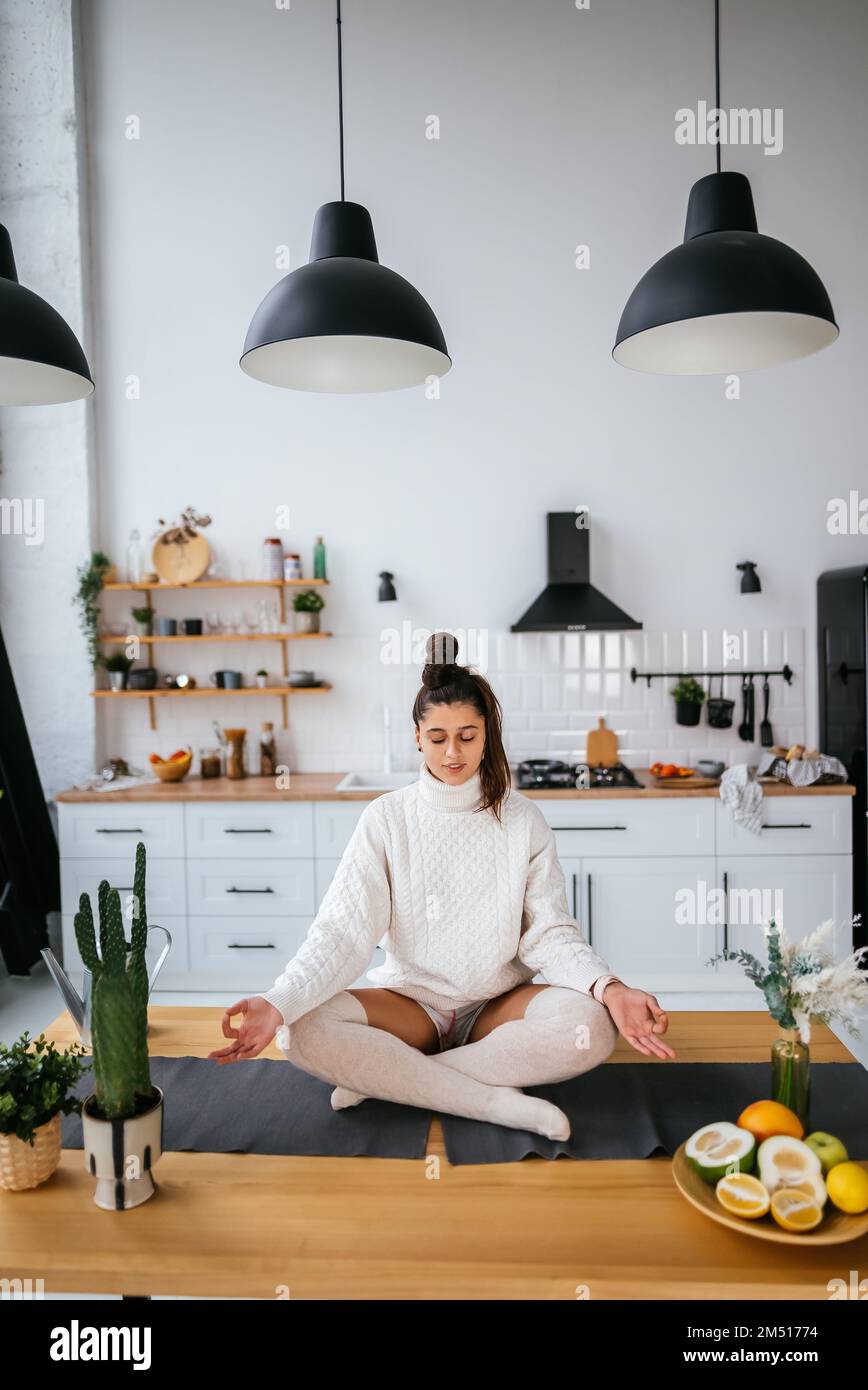 Young woman in lotus position sitting on the table Stock Photo - Alamy