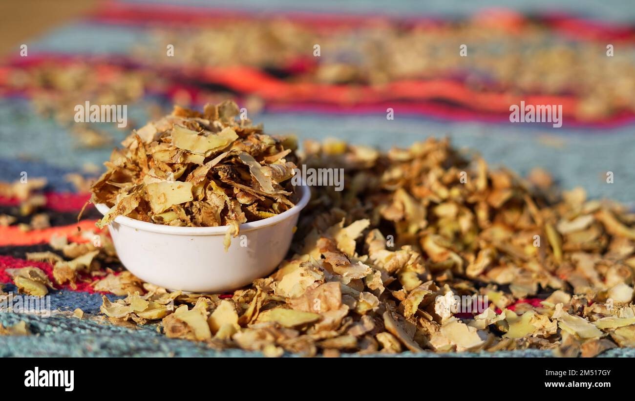 A pile of Ginger roots peeled with knife over chopping block. Ginger or ...