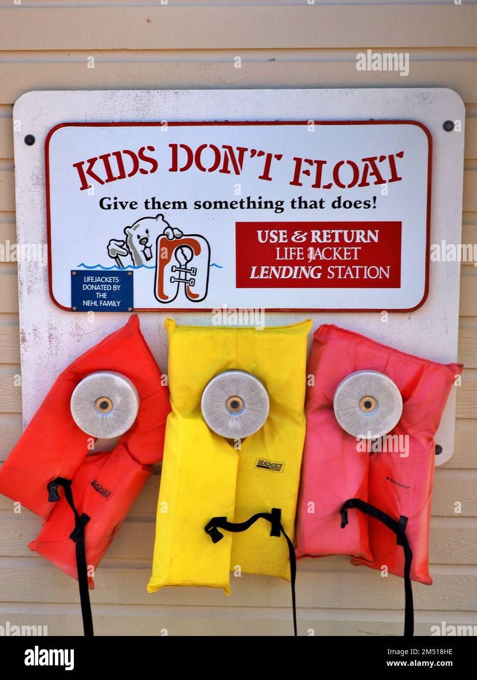 A vertical shot of "kids don't float" sign with colorful life jackets ...