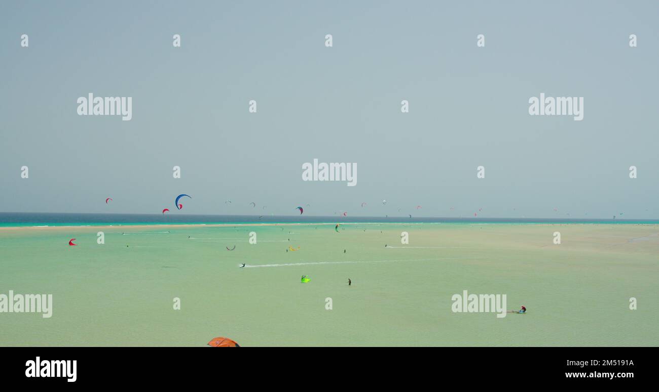 Wide shot showing group of kite surfer kiteboarding on waves of ...