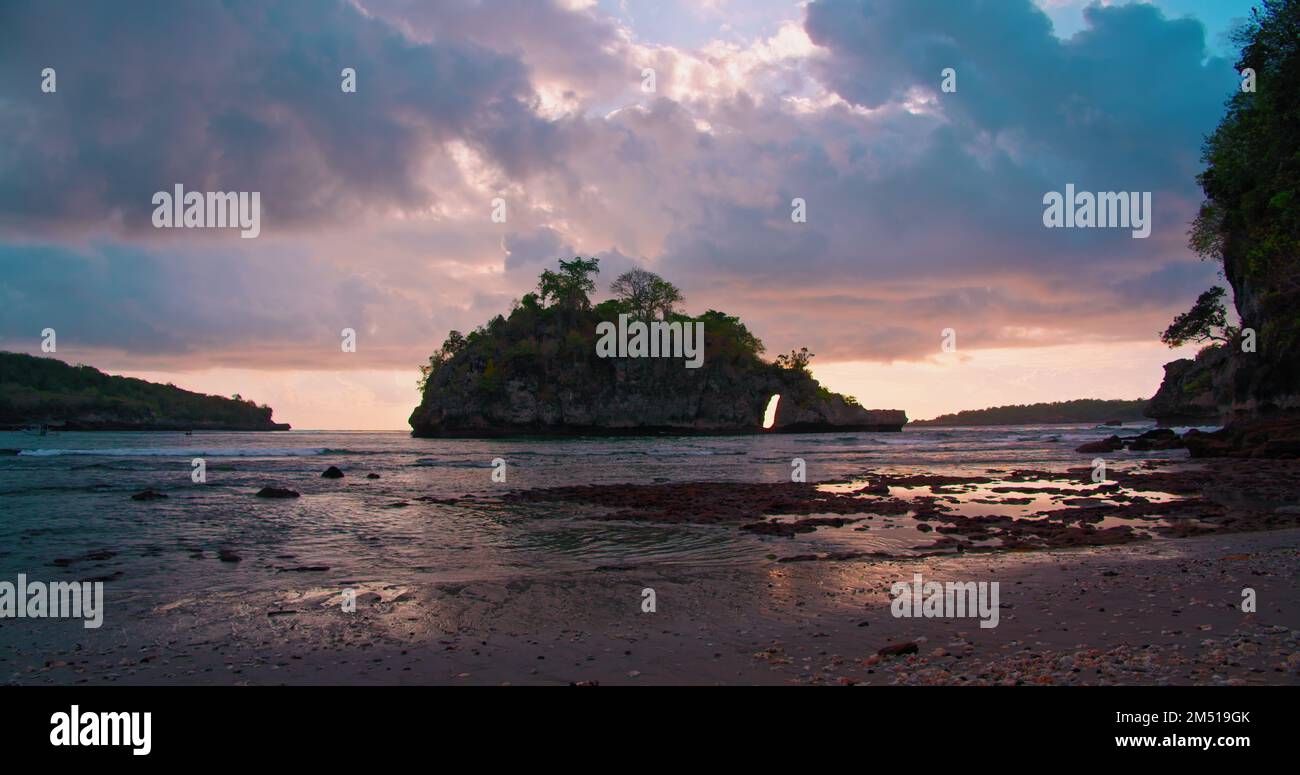 Island silhouette at sunset in shallow calm ocean water with dark ...