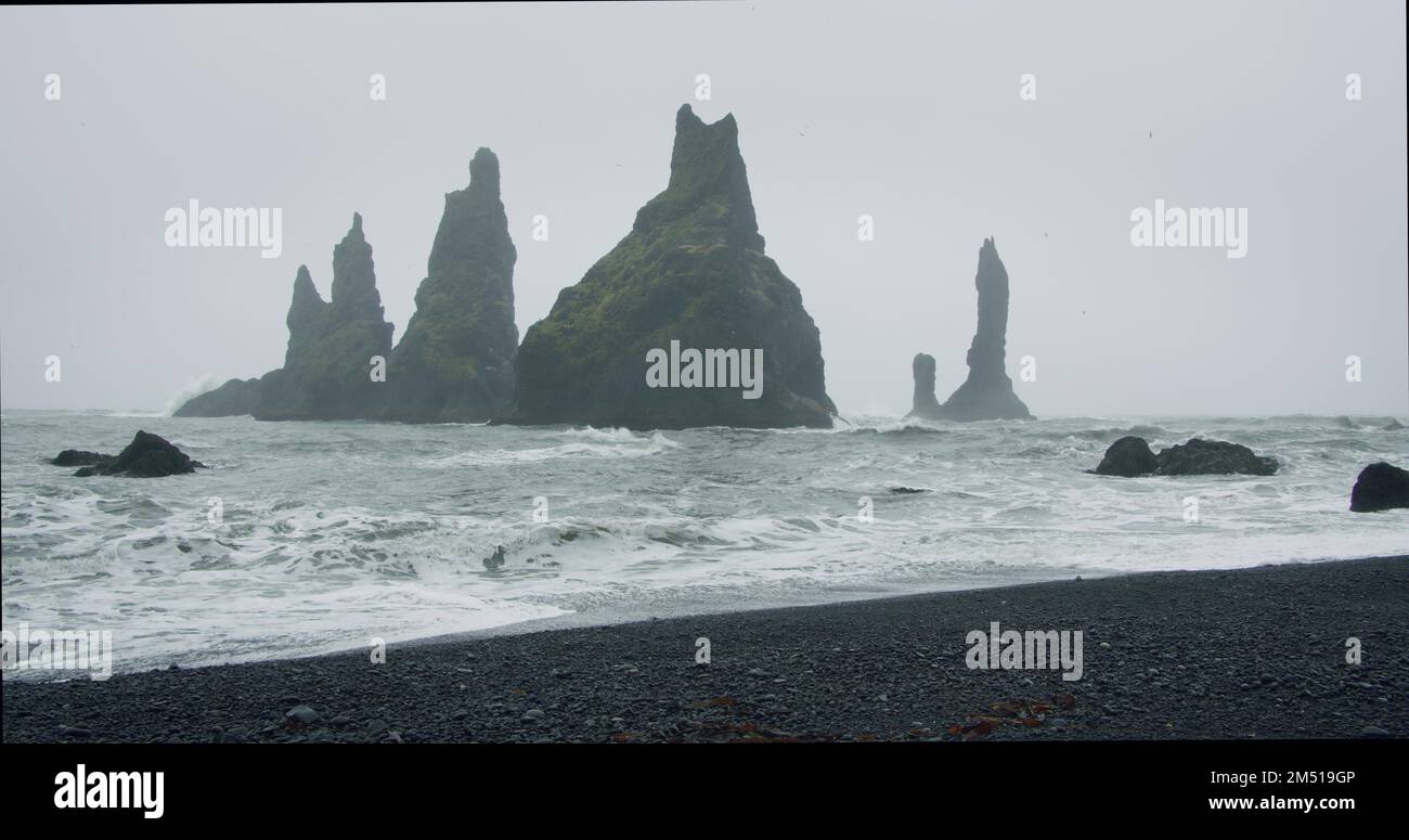 The black sand beach of Reynisfjara with waves hitting the shore on ...