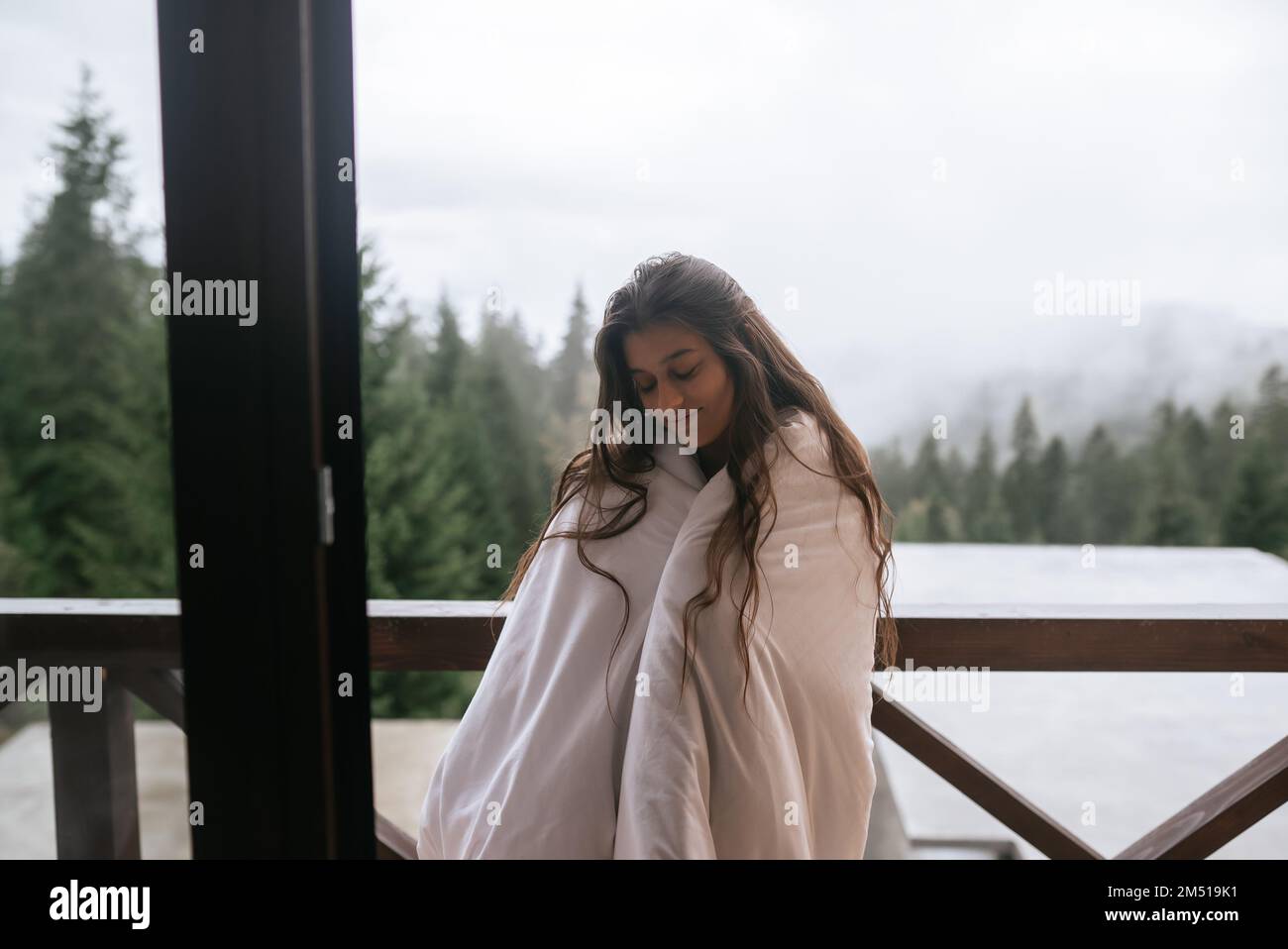 Young woman wrapped in a blanket on the balcony Stock Photo - Alamy