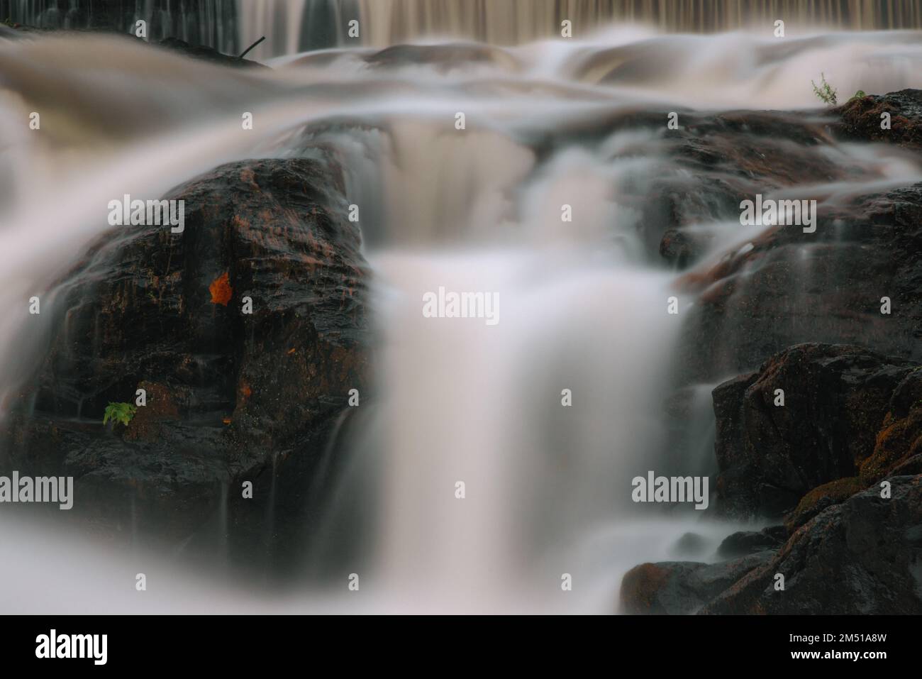 A long exposure shot of a cascade waterfall coming down the big rocks ...