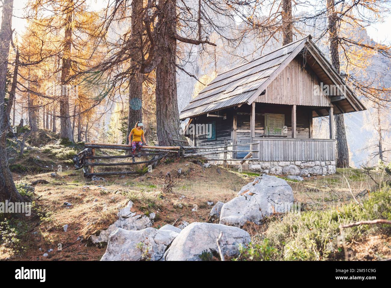 Onle lonley woman hiker sitting on a fence by a wooden house in the ...
