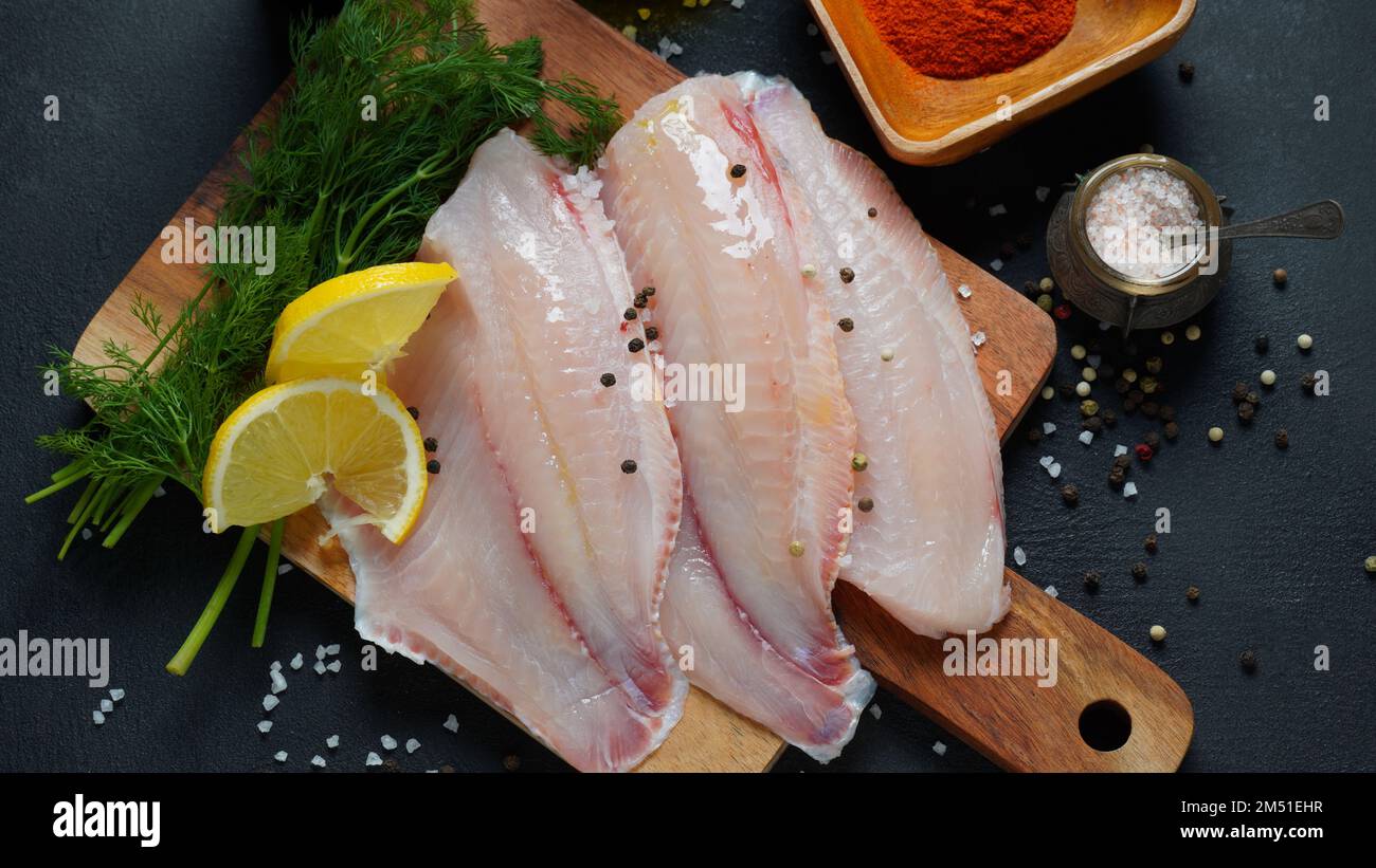 Fresh red tilapia fish fillet sliced for steak or salad with herbs ...