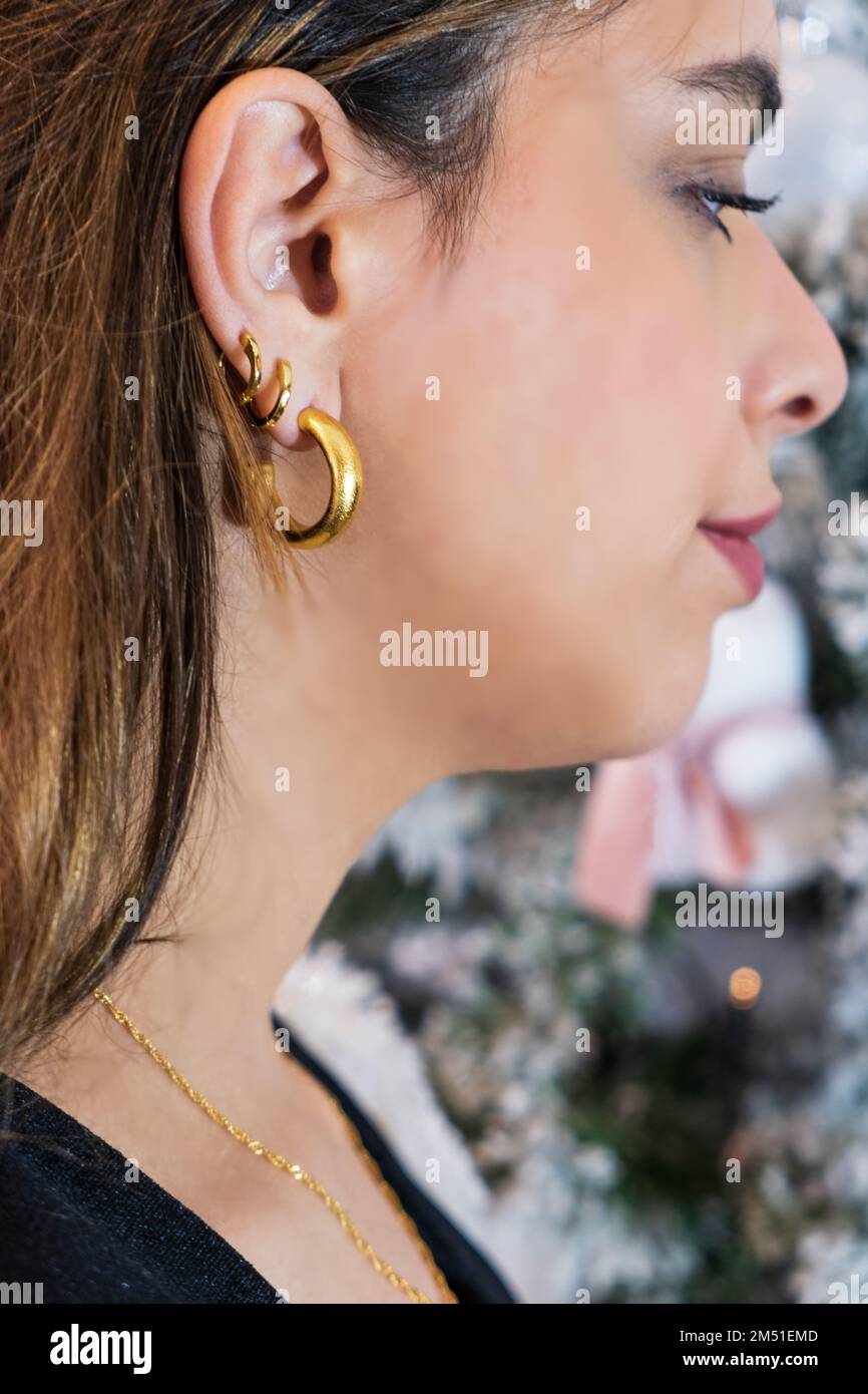 Woman wearing golden earrings and necklace standing infront of a ...