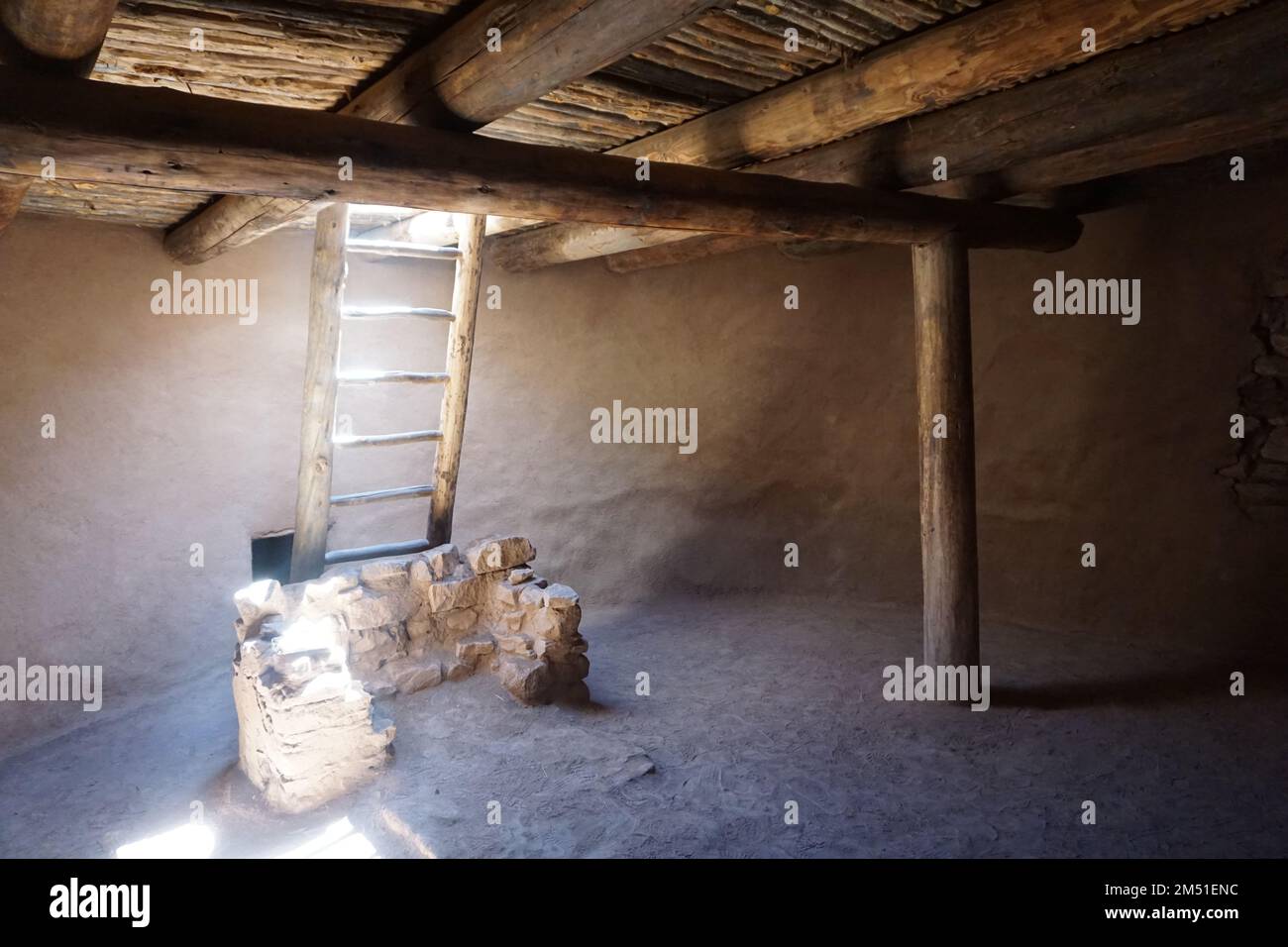 Inside of underground Native American kiva with a ladder and sunlight ...