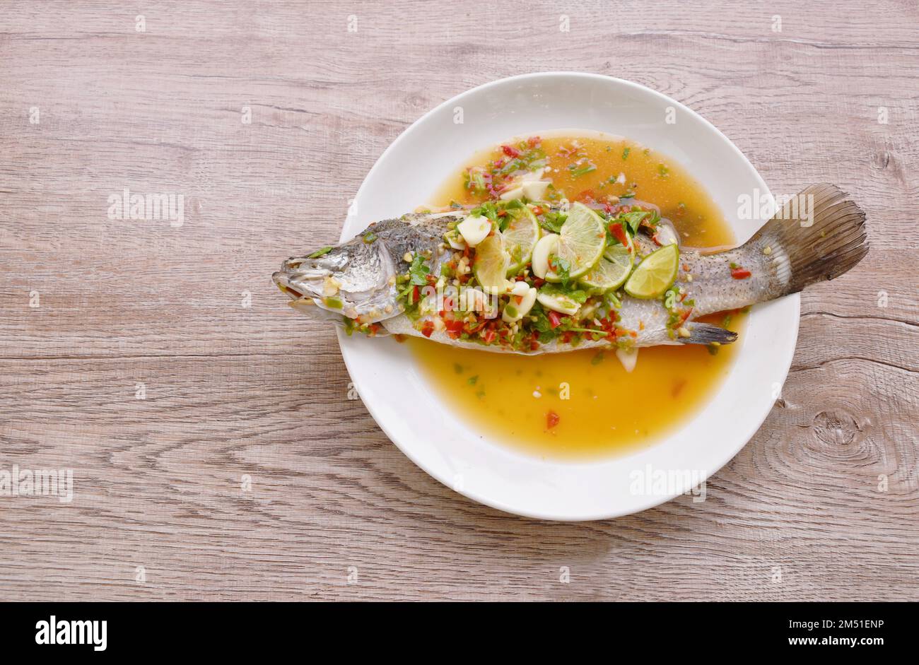 steamed bass fish dressing lemon sweet and sour chili sauce on plate ...