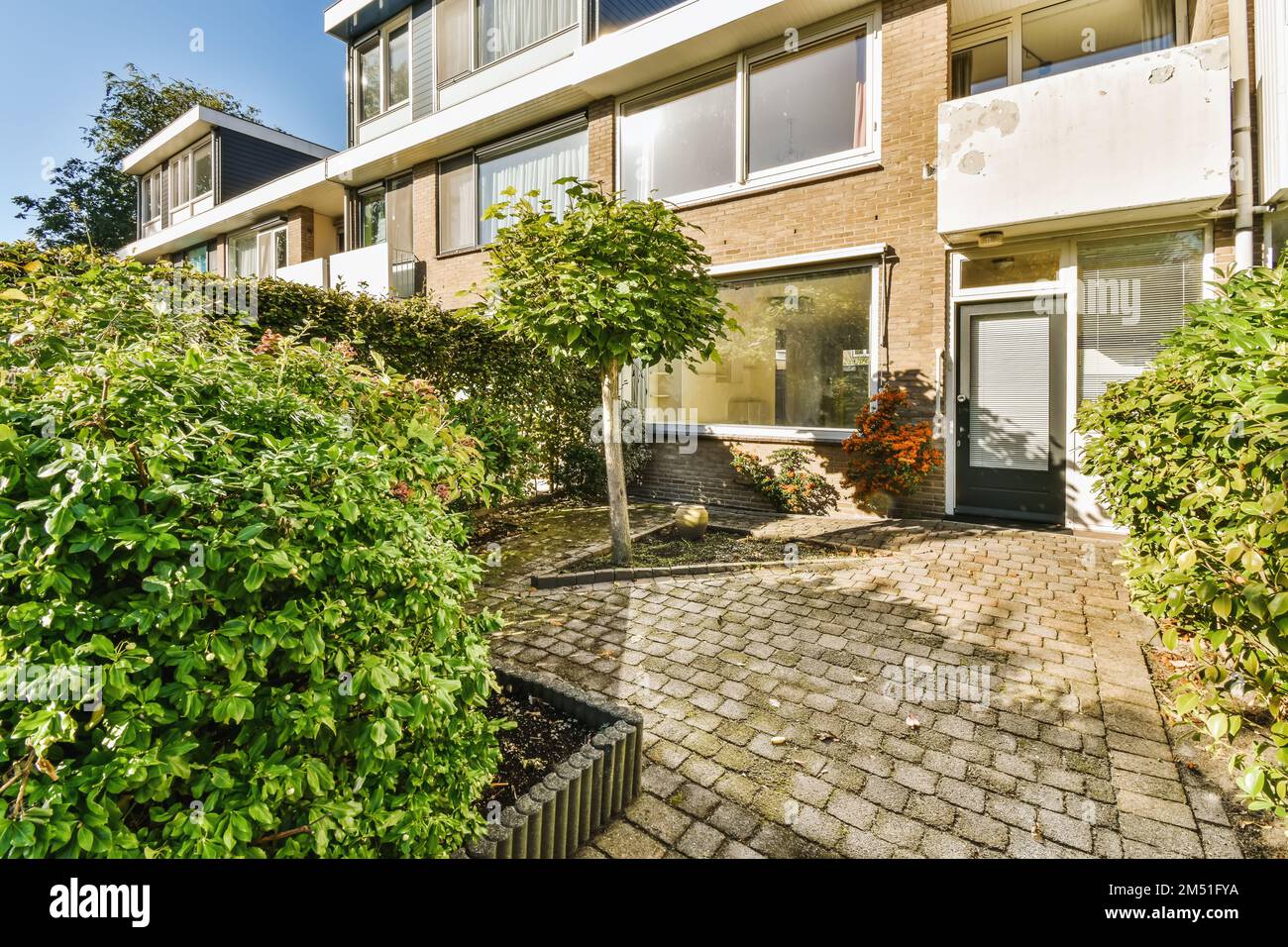the outside of an apartment building with trees and bushes in front of ...