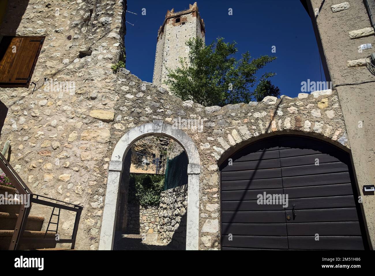 Tower of the Scaligero castle framed by buildings seen from a square at ...