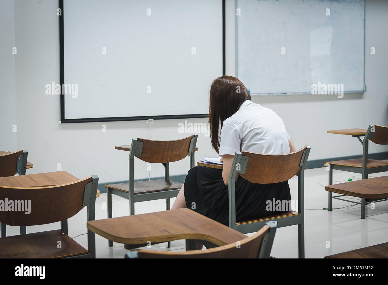 A female college student writing on final examination papers in a ...
