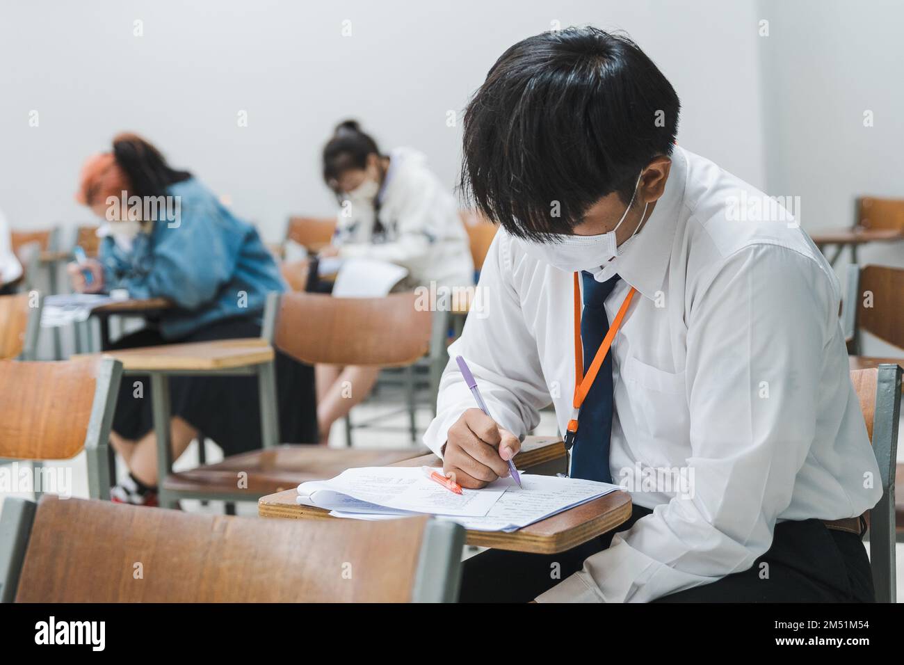 College students concentratively writing on final examination papers in ...