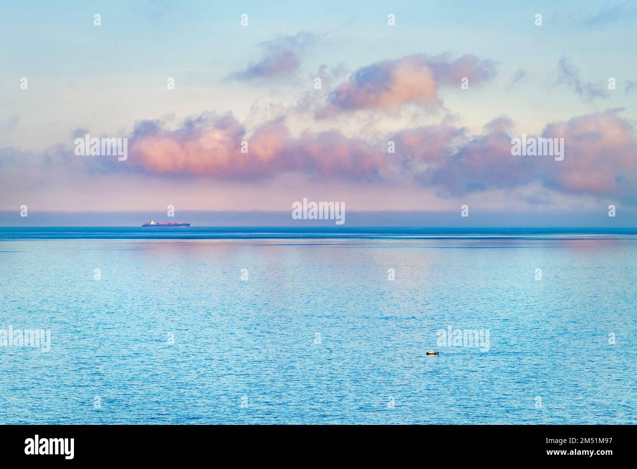 Ocean scenery including some clouds and a distant container ship at ...