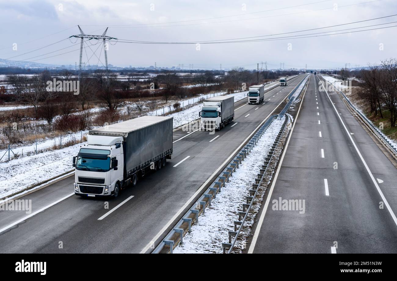 Convoy of Transportation Lorry Trucks on a Highway in a snowy winter ...