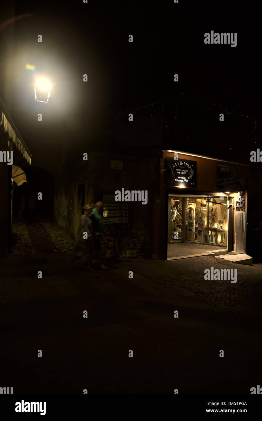Cobbled narrow street with lit shop windows at night Stock Photo - Alamy
