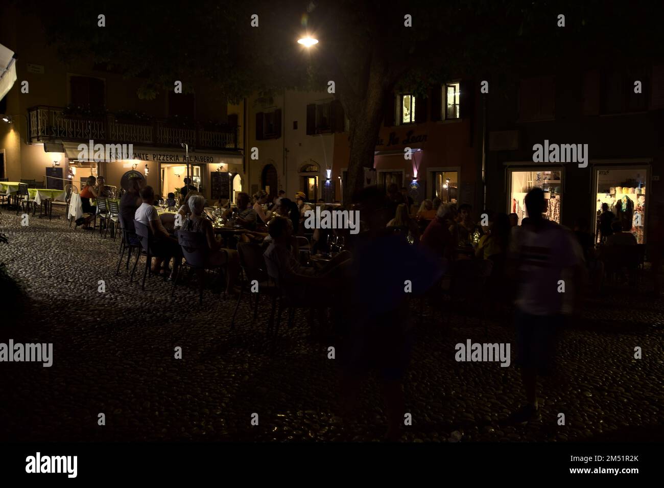 Square with restaurant and people dining at night Stock Photo - Alamy