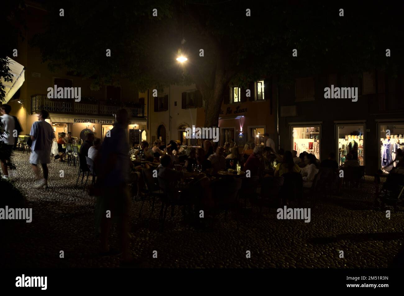 Square with restaurant and people dining at night Stock Photo - Alamy