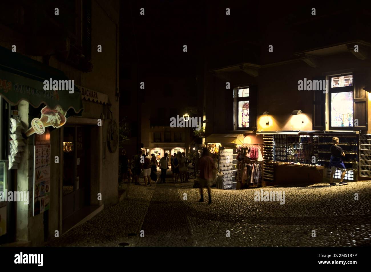 Cobbled narrow street with lit shop windows at night Stock Photo - Alamy