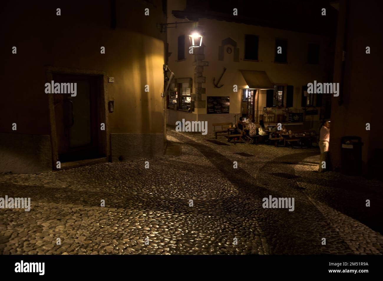 Square with restaurant and people dining at night Stock Photo - Alamy