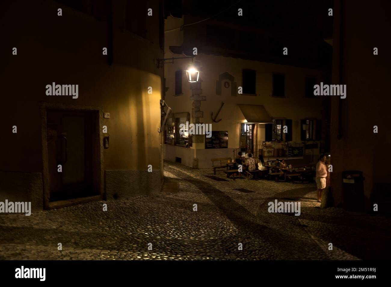 Square with restaurant and people dining at night Stock Photo - Alamy