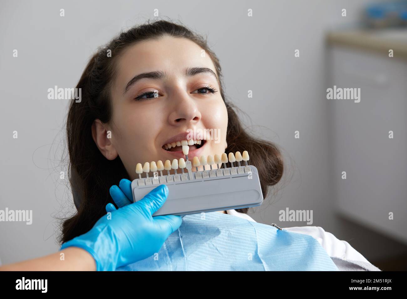 Dentist choosing color tone of tooth enamel for patient. Dentist ...