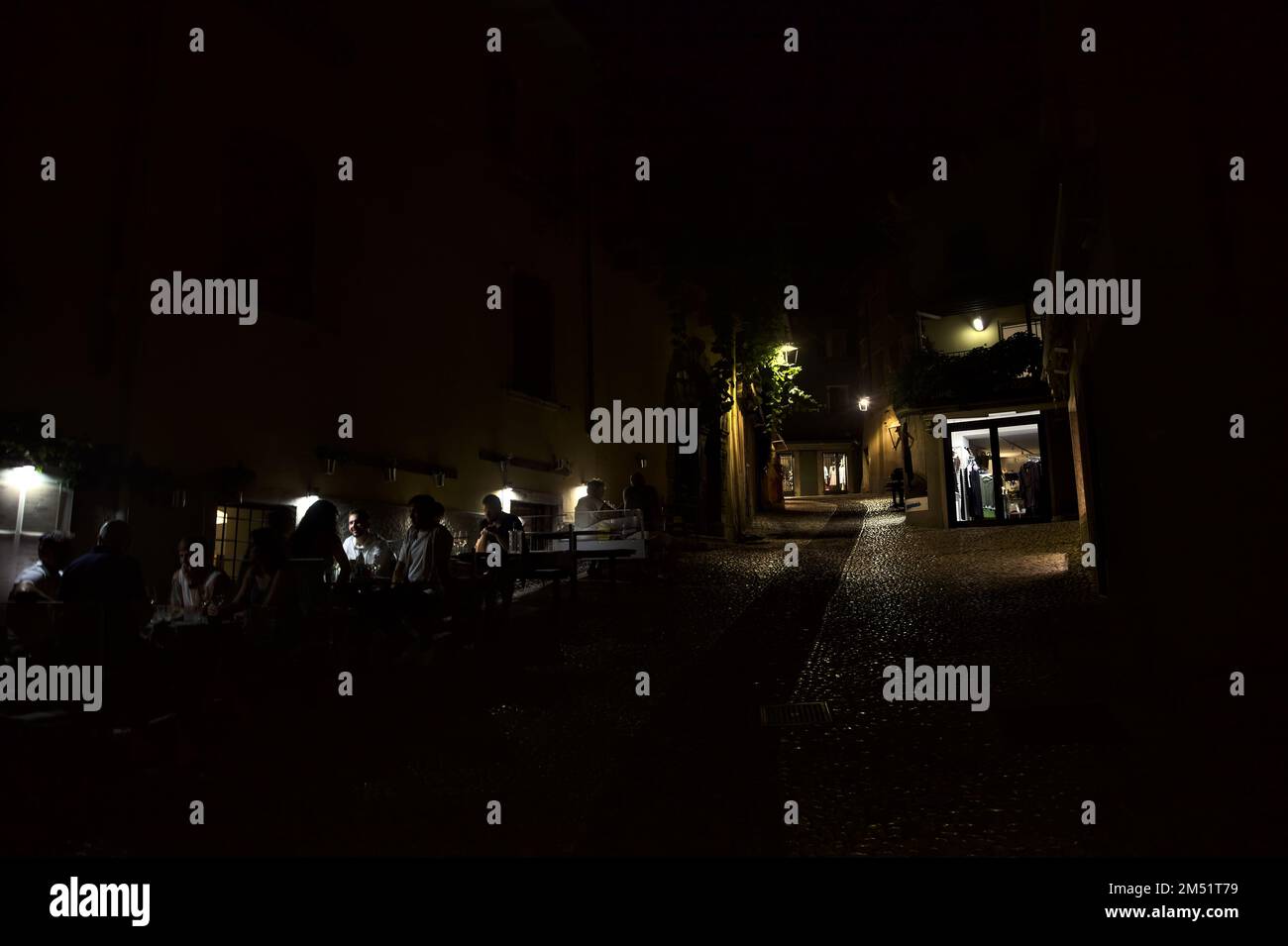 Square with restaurant and people dining at night Stock Photo - Alamy