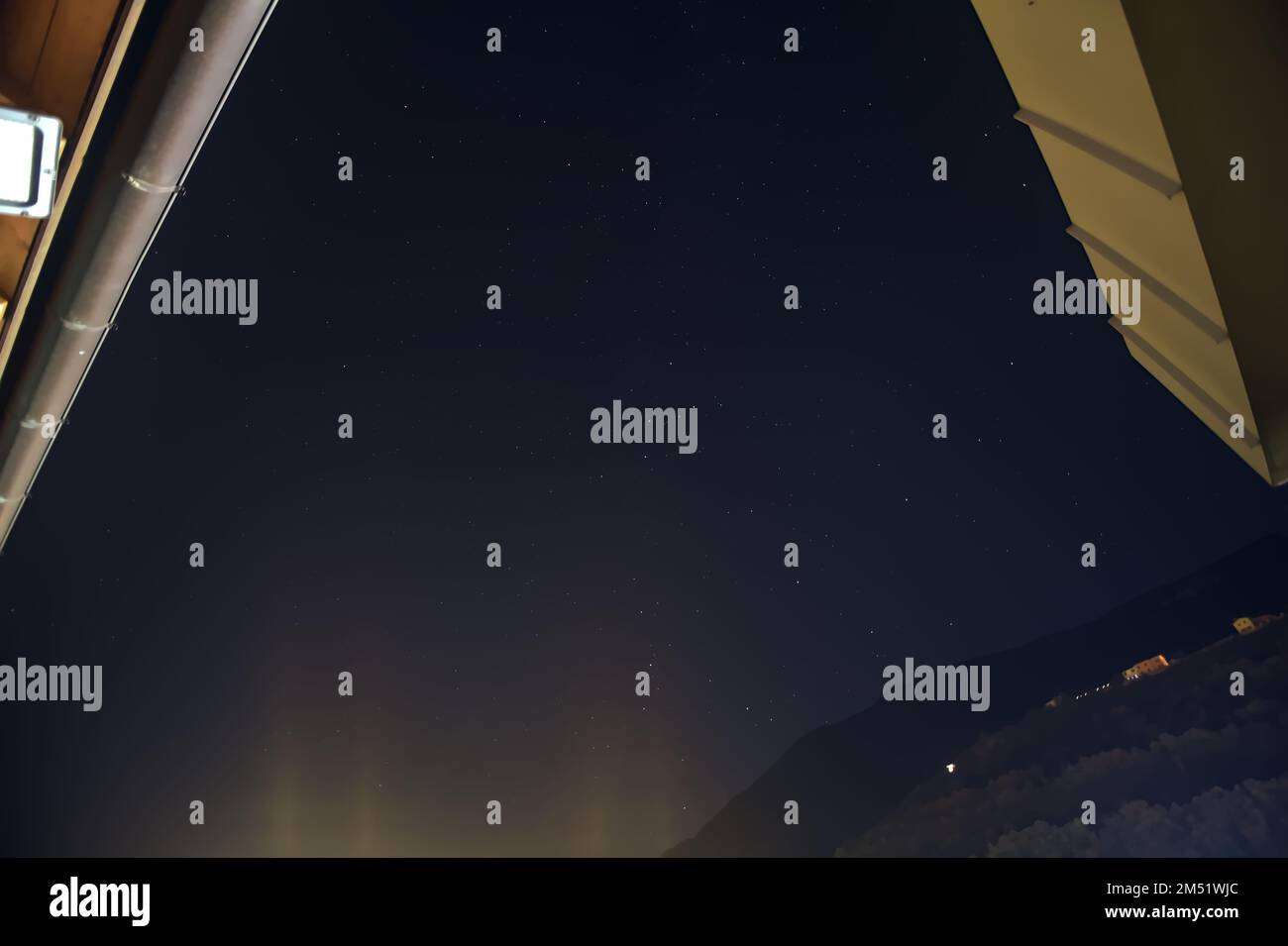 Clear sky at night with stars framed by a building and a mountain ridge ...