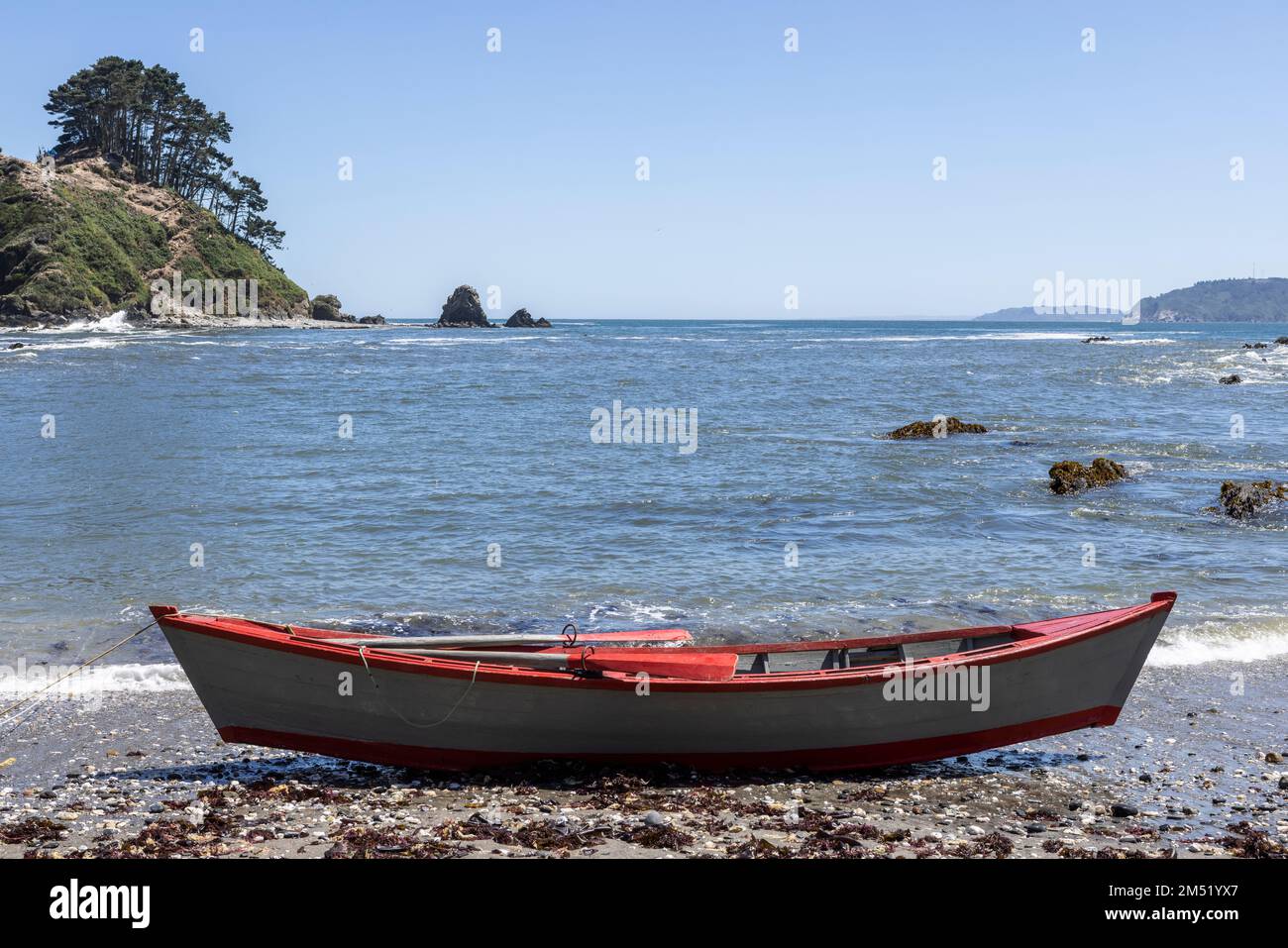 Red and white painted rowing boat at the beach at Isla Maiquillahue in ...