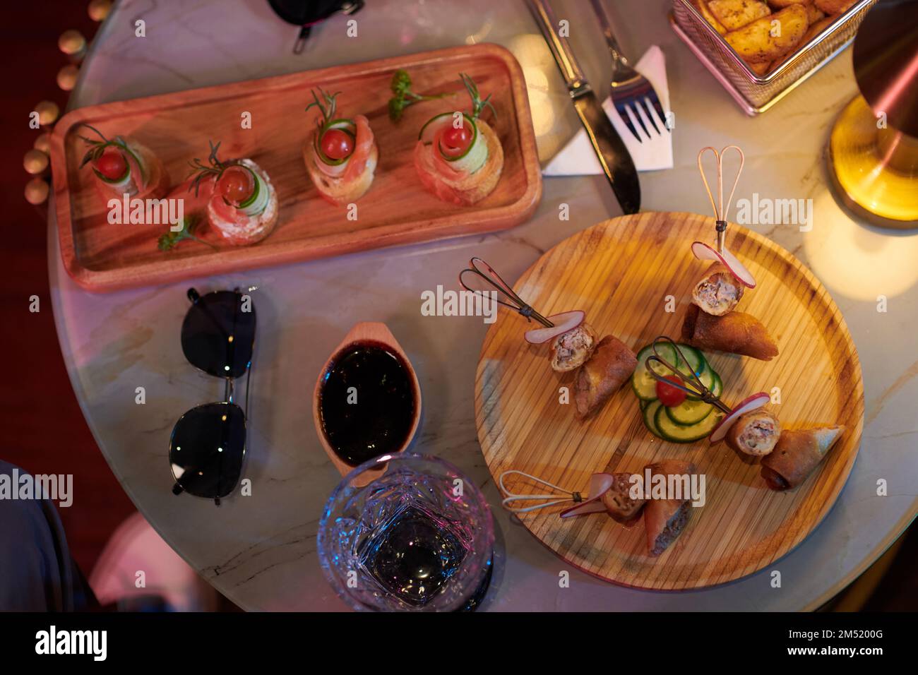 Wooden plates with tasty snacks on round table served for group of ...